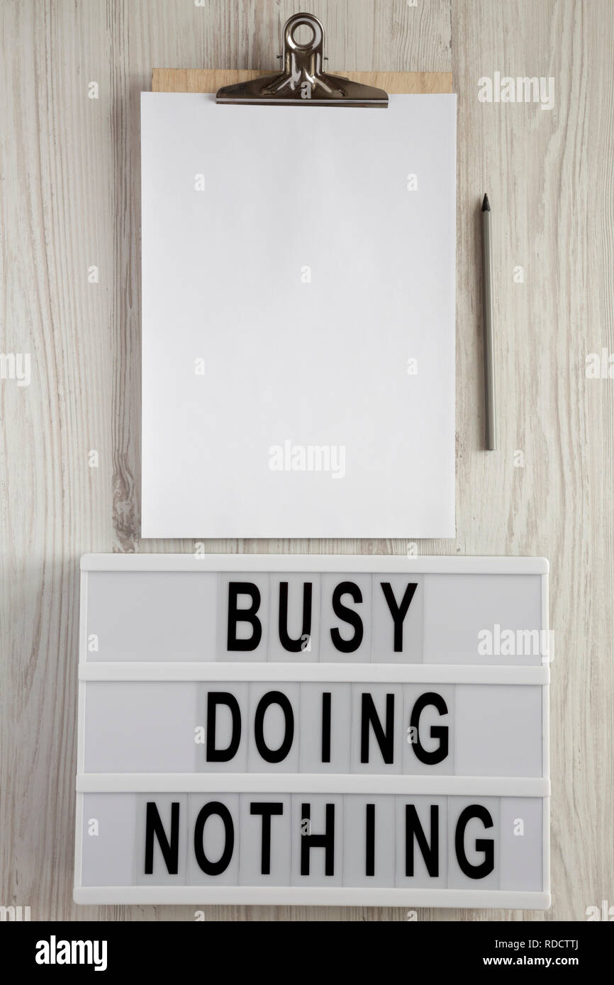 Modern box with text 'Busy doing nothing', noticepad and pencil on a ...