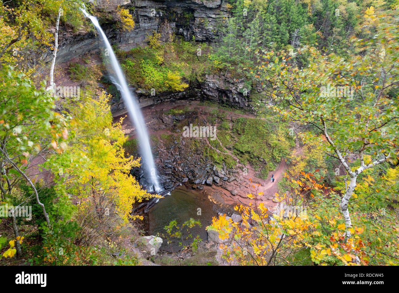 Three people gathered at the base of Upper Kaaterskill Falls ...