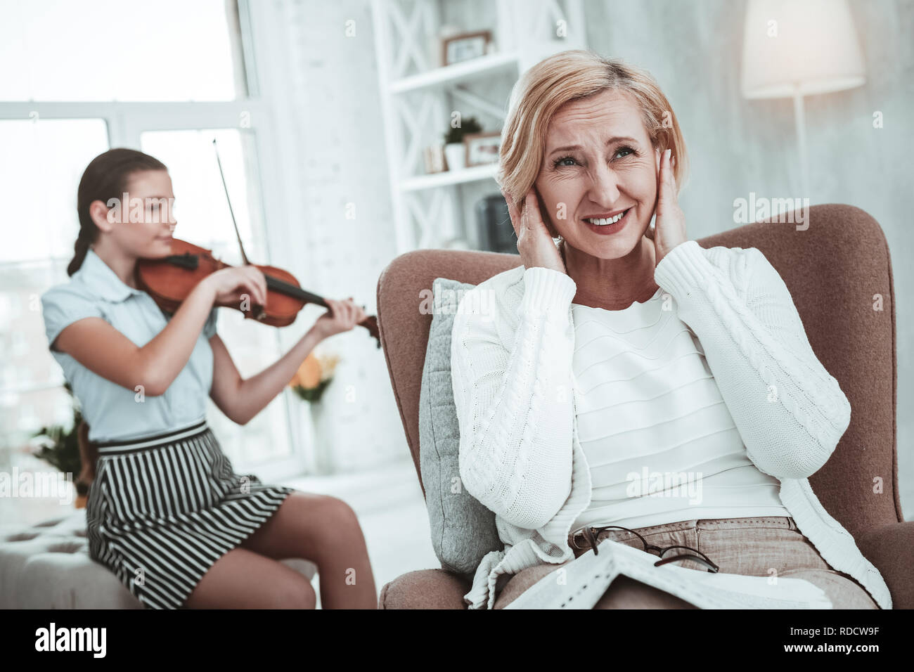 Cheerless unhappy blonde woman covering her ears Stock Photo - Alamy
