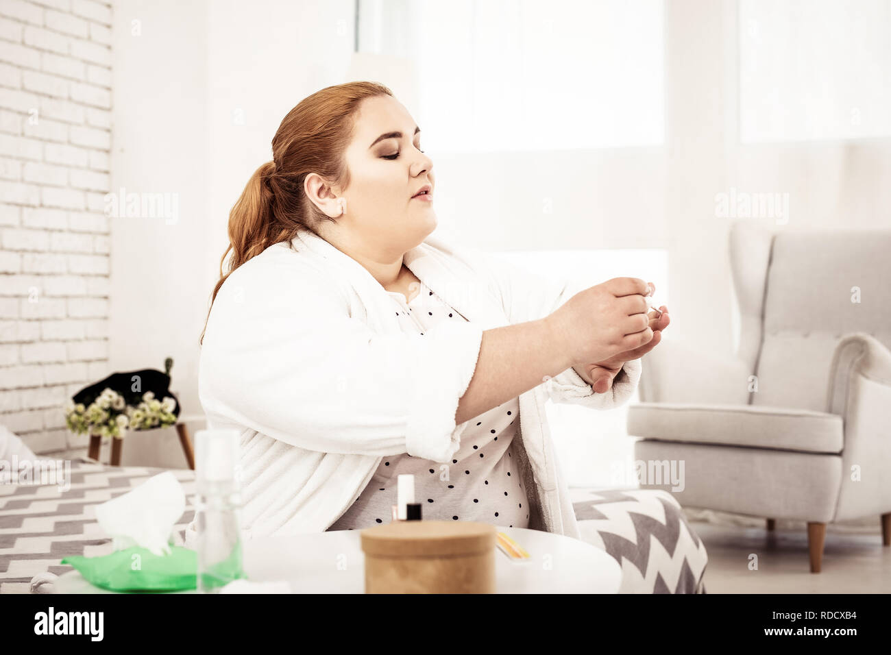 Concentrated plus size woman applying nail polish Stock Photo - Alamy