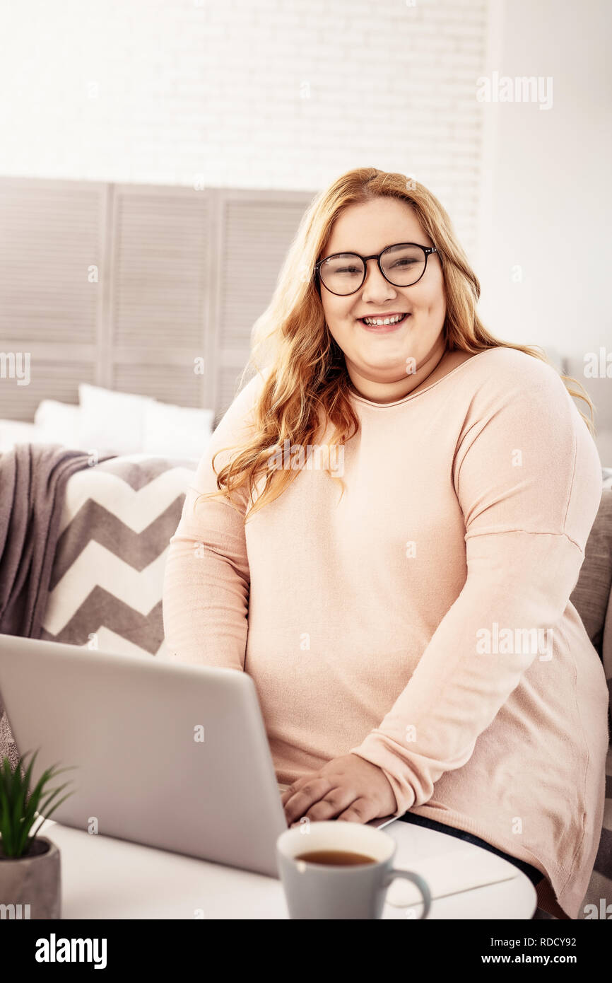 Openly laughing plus-size woman working as freelancer from home Stock ...