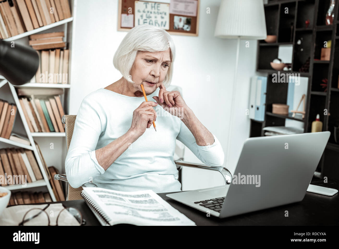 Serious senior woman trying to concentrate on project Stock Photo - Alamy