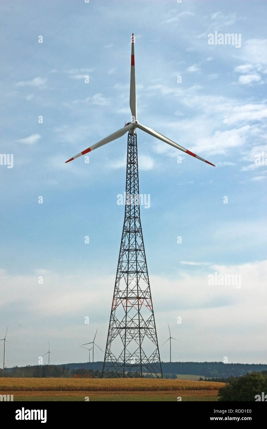 wind turbine with lattice mast in front of blue sky, further windmills ...