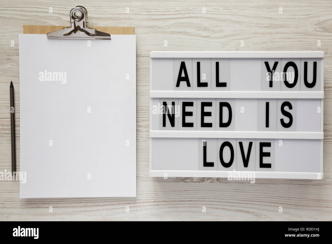 Modern board with text 'All you need is love', noticeboard with pencil ...