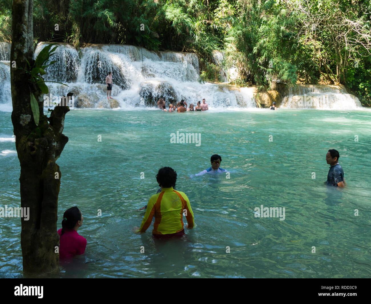Tourists cooling off in clear water pool of three tiered Tat Kuang Si ...