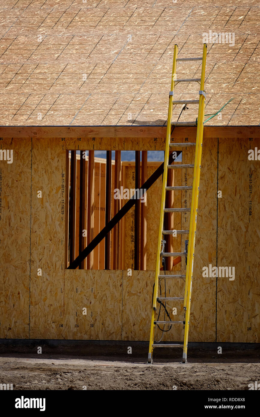 Construction site with yellow ladder with rough boards against wall ...