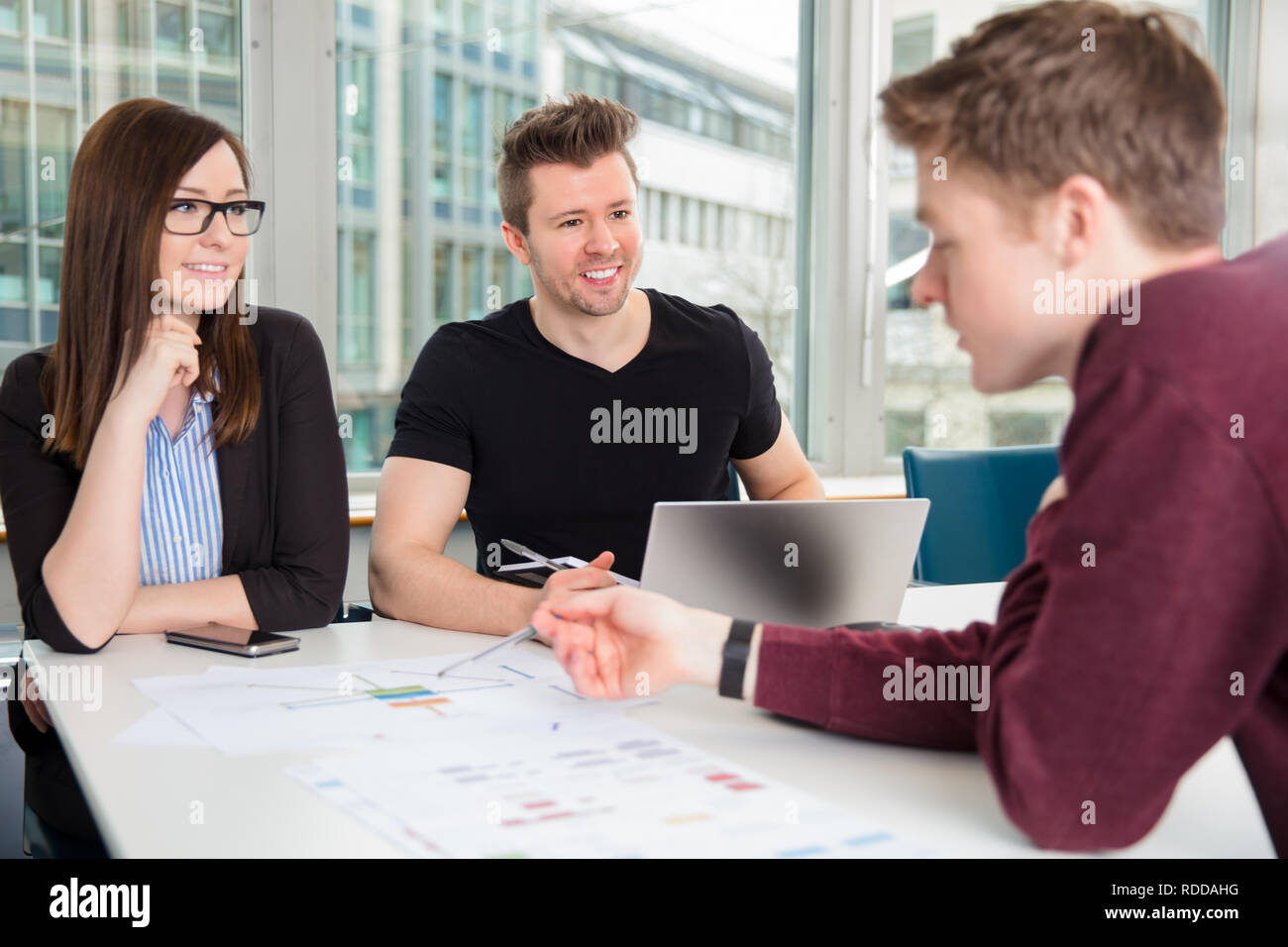 Smiling Business People Looking At Colleague Explaining Chart At Stock ...