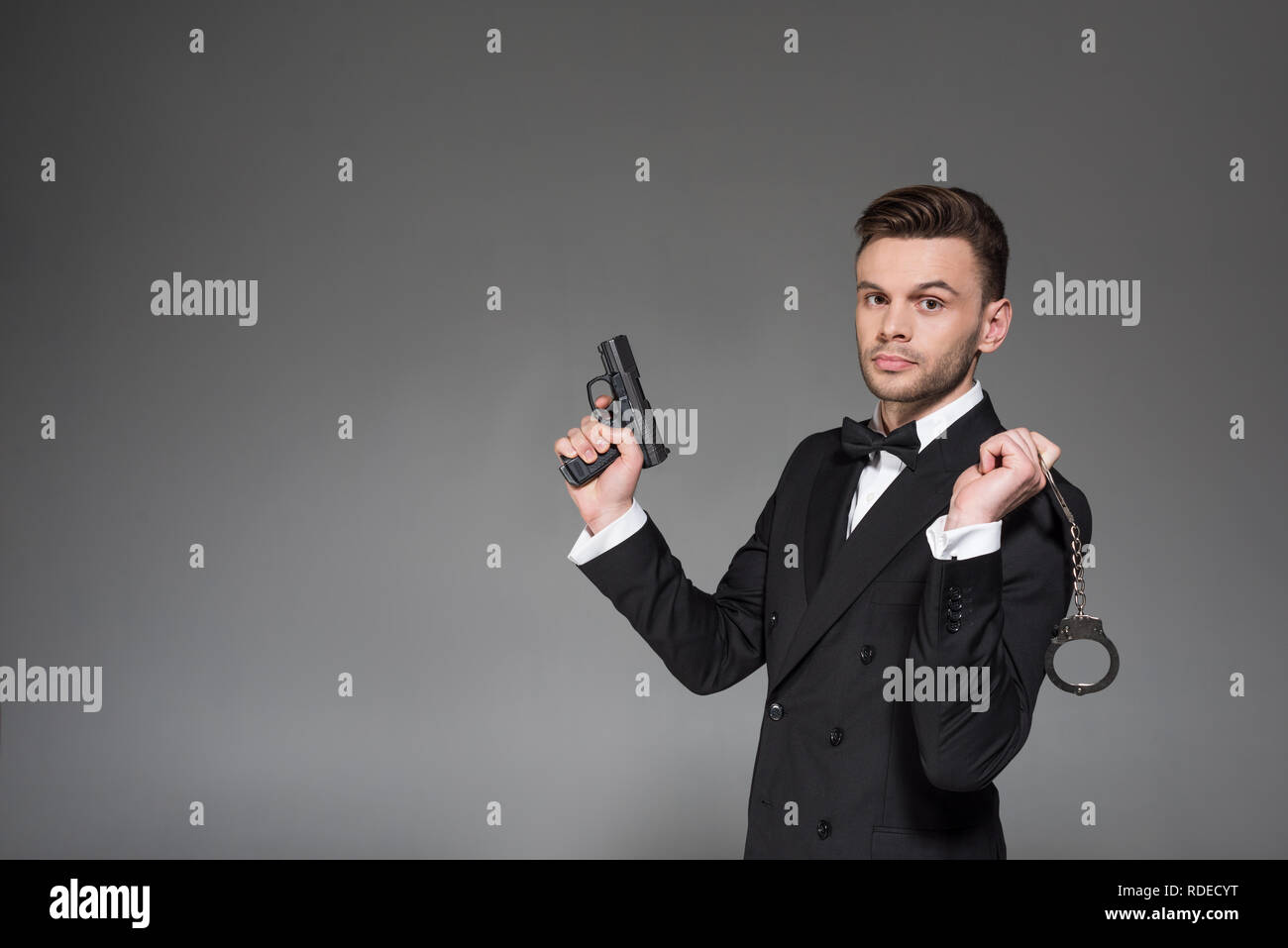 handsome secret agent in black suit holding handgun and handcuffs ...