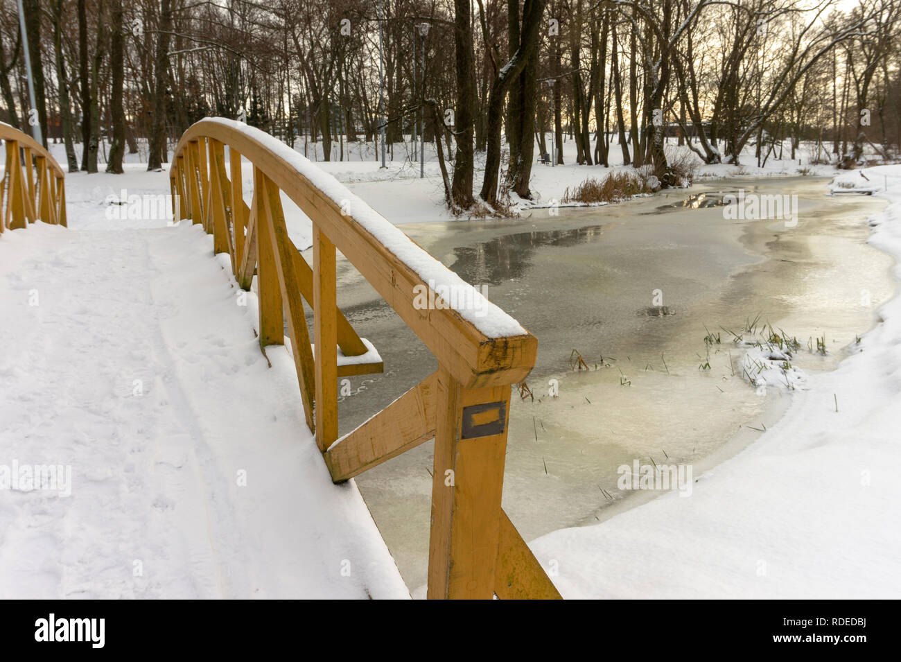 Unmoving frozen snowy river underneath wooden bridge with railing ...