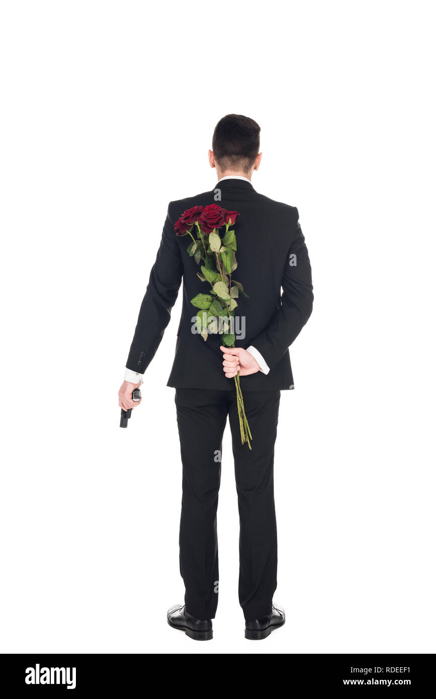 back view of secret agent in black suit holding handgun and red roses ...