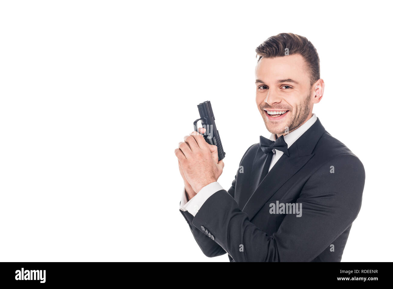 cheerful secret agent in black suit holding gun, isolated on white ...