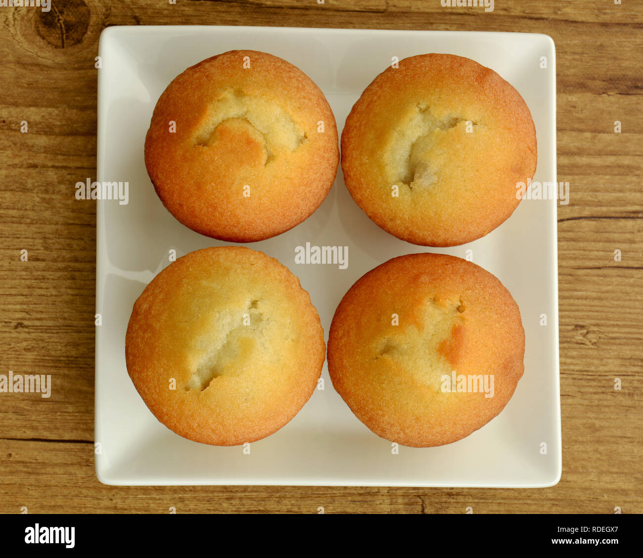 Fresh baked golden muffins on square white plate shot from overhead in ...