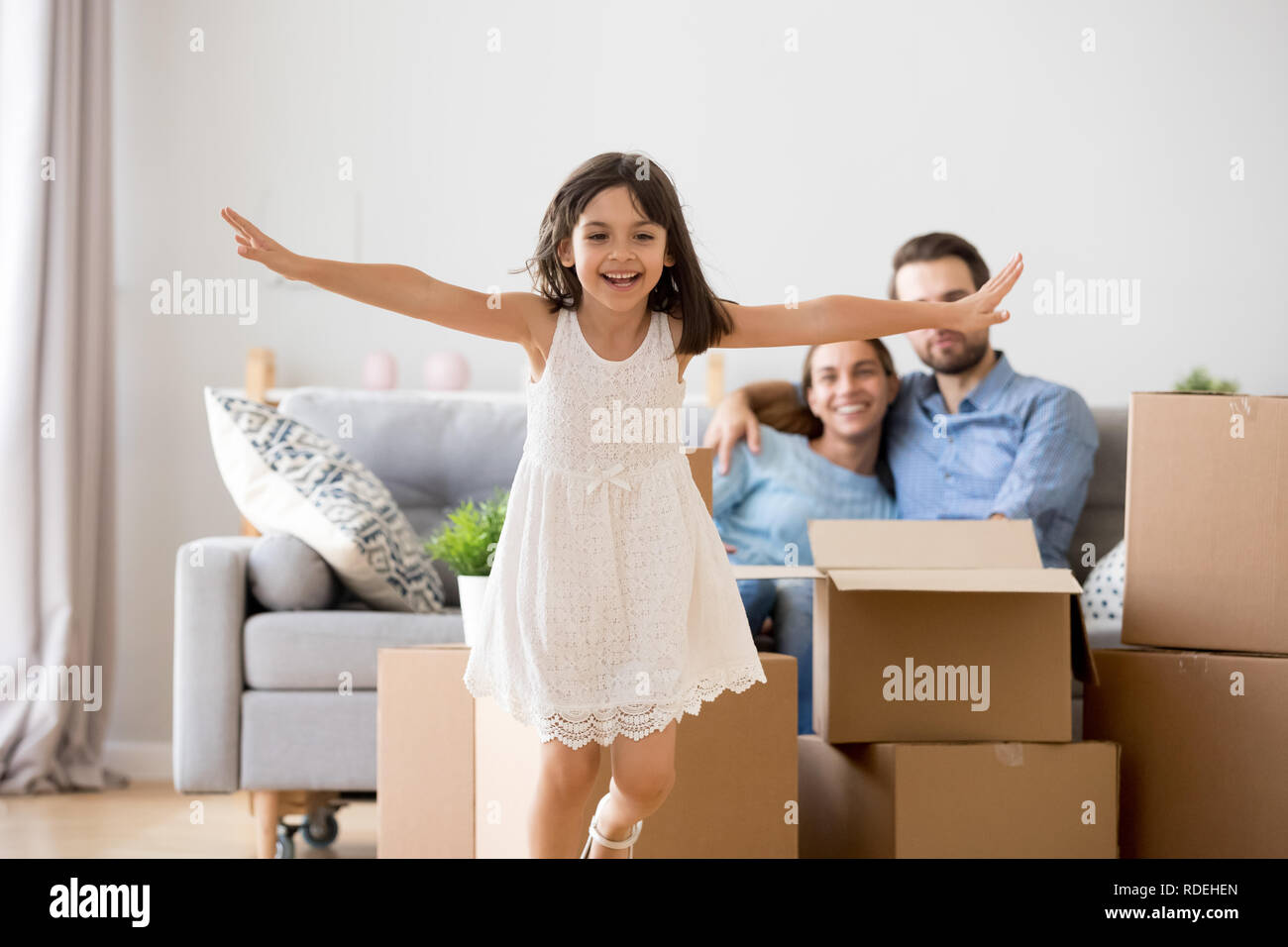 Excited kid girl running over living room enjoying moving day Stock ...