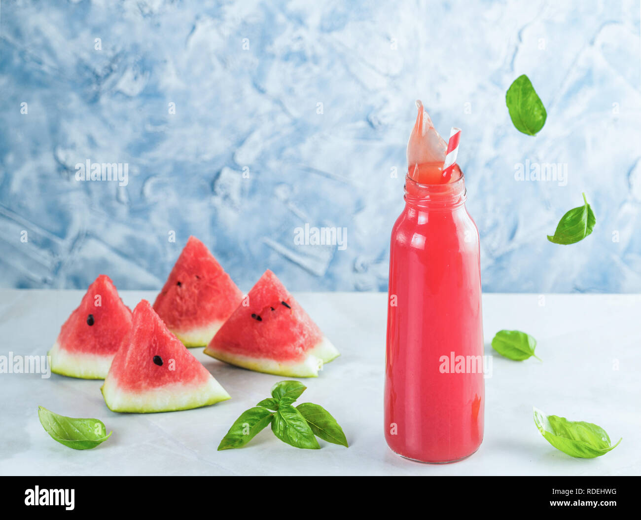 Tasty appetizing watermelon drink with basil in glass bottle on gray ...