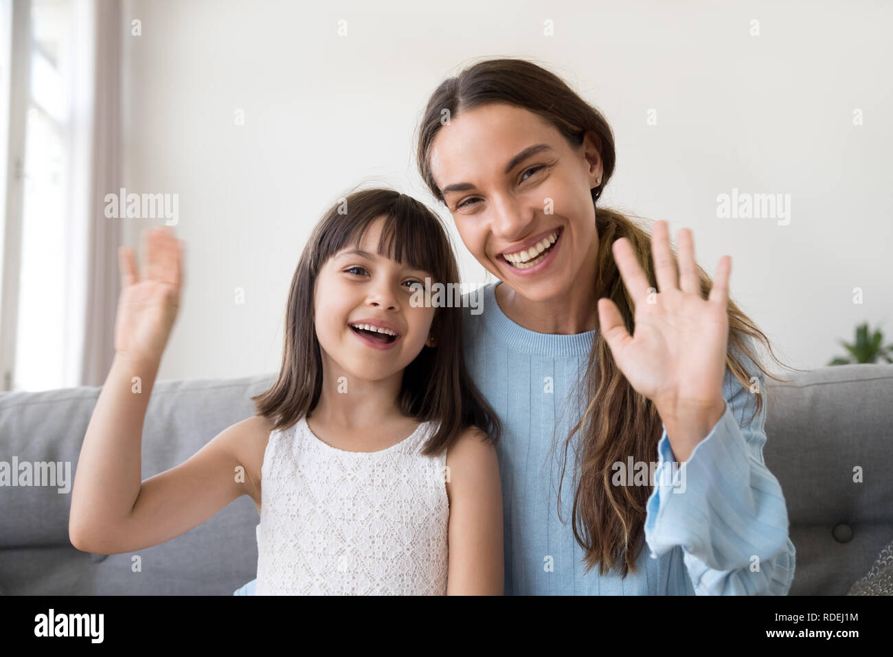 Happy mom and kid daughter waving hands looking at camera Stock Photo ...