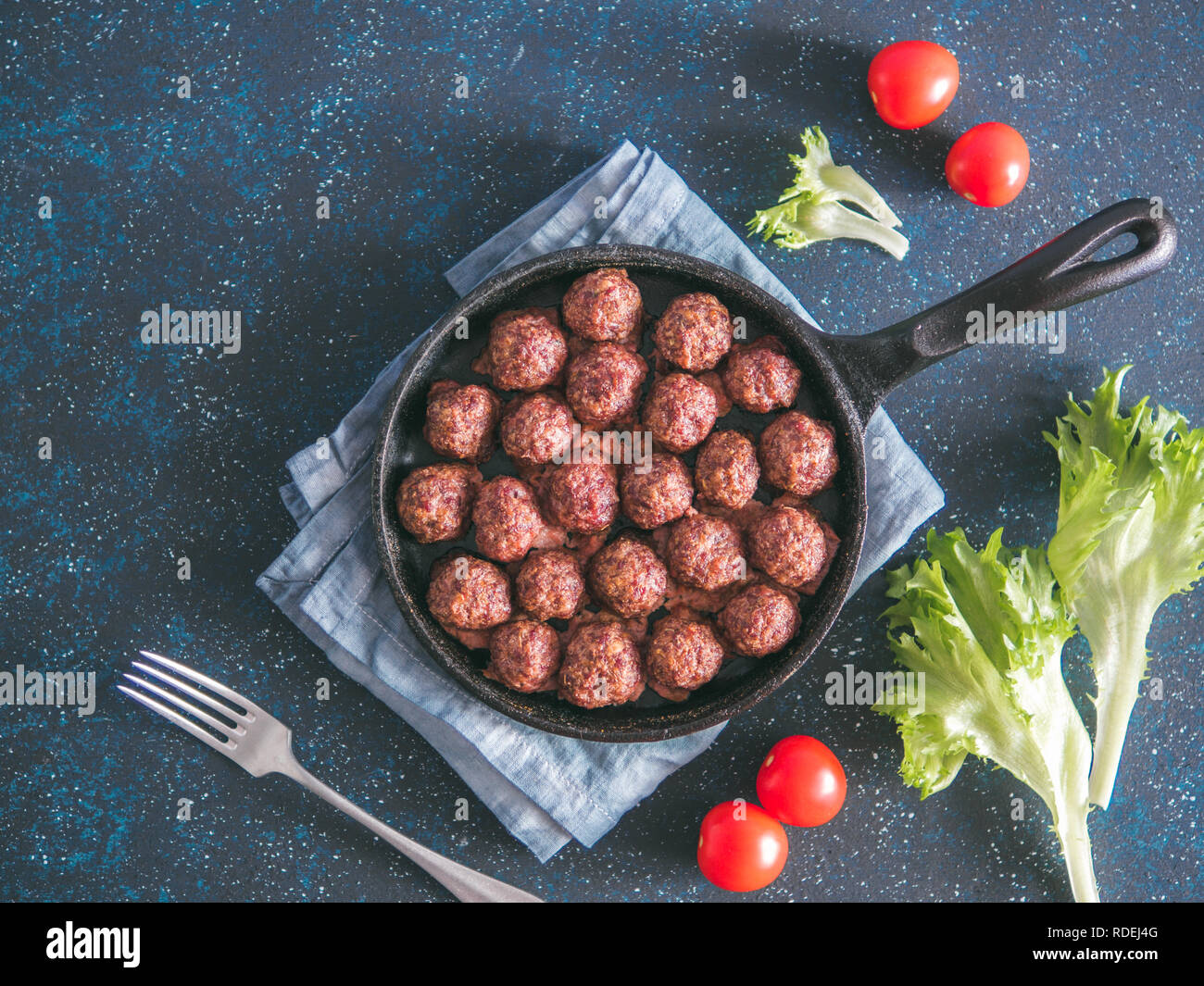 Homemade roasted beef meatballs in cast-iron skillet on dark blue ...