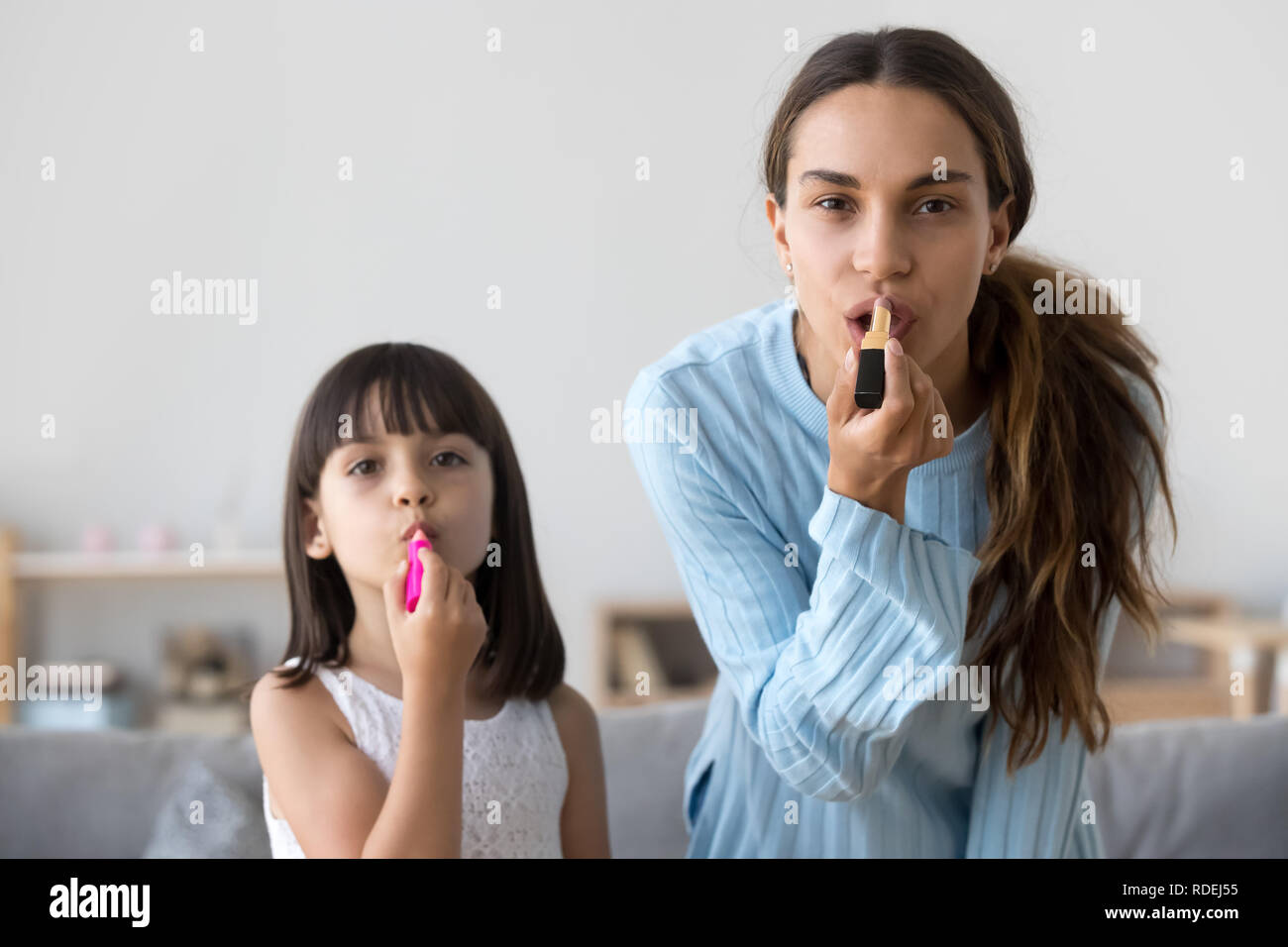 Funny kid girl applying lipstick doing makeup copying mom, portr Stock ...