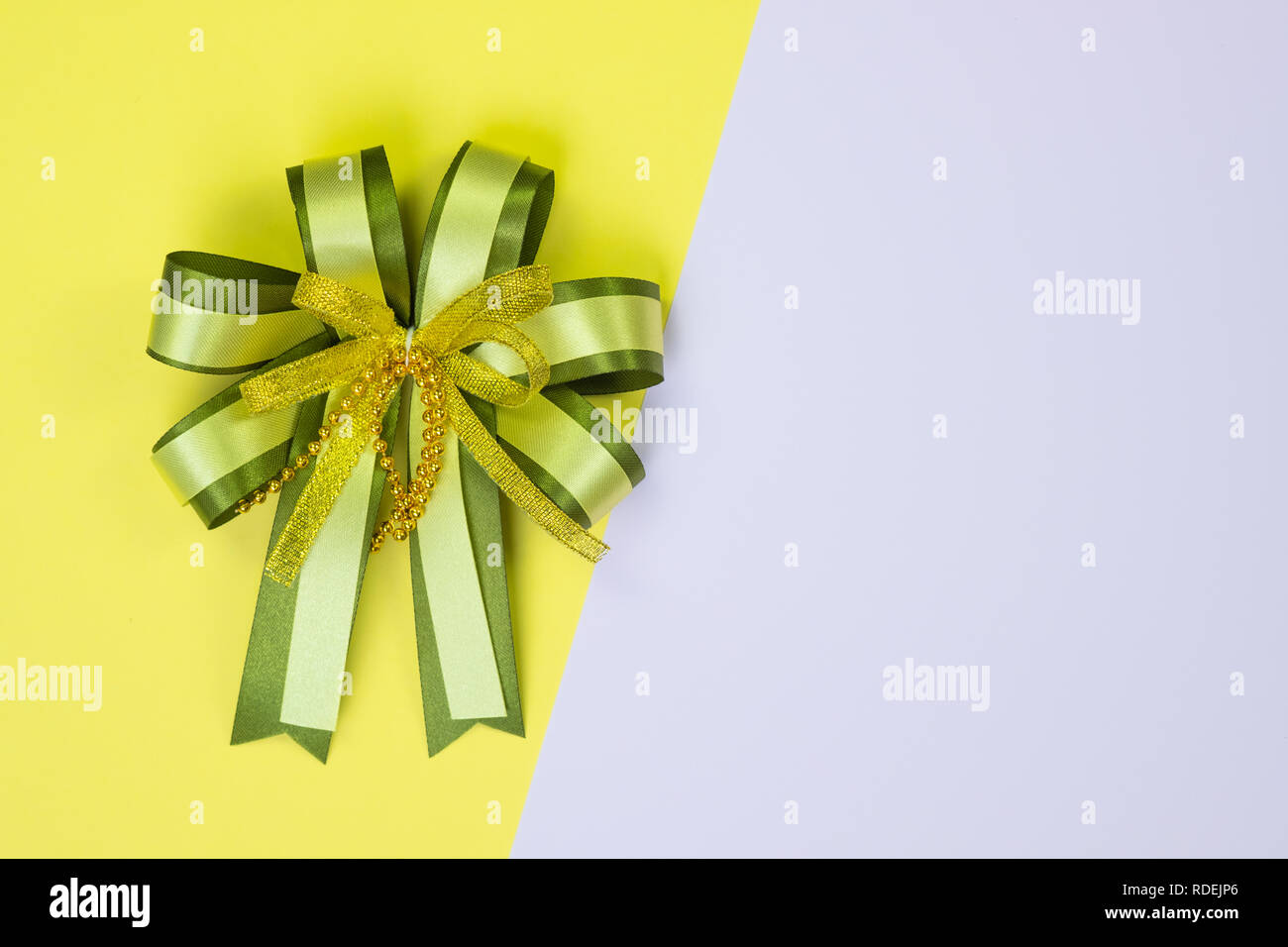 Decorative green ribbon bow on sweet pastel colored paper background ...