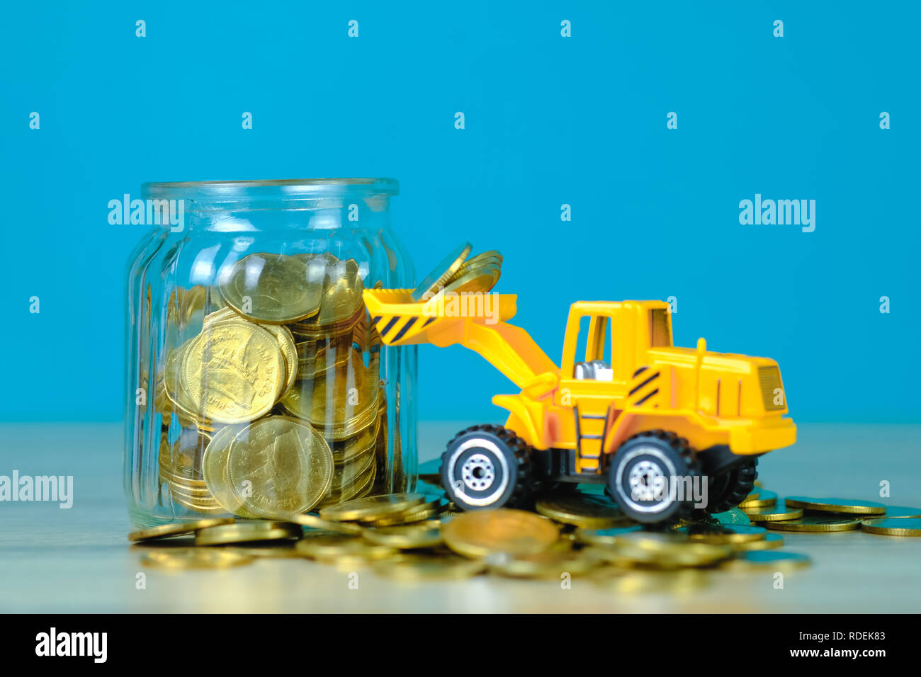 Mini bulldozer truck loading stack coin with pile of gold coin to glass ...