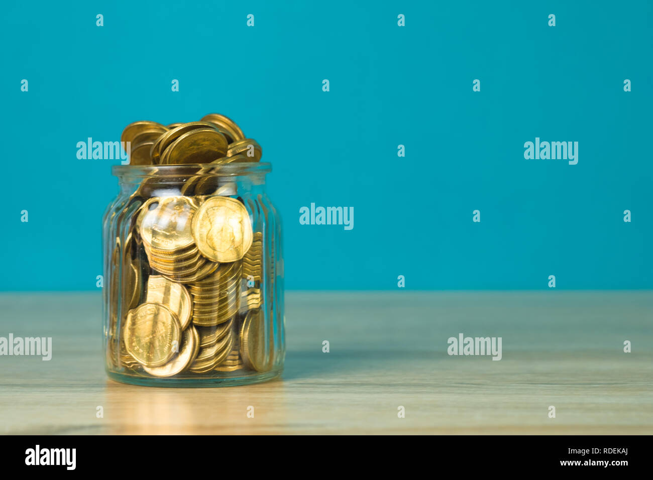 Coin money in the glass jar on table with green background, for saving ...