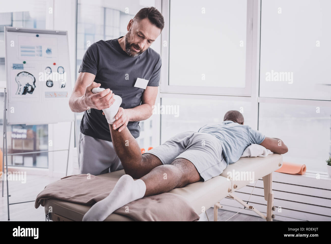 Serious young medical worker examining injured foot Stock Photo - Alamy