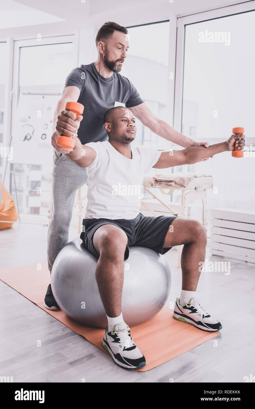 Concentrated young man training his muscles in gym Stock Photo - Alamy