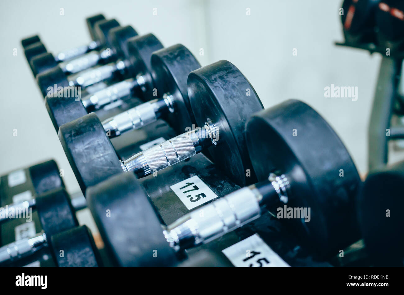 Metallic or steel heavy dumbbells for weight training on stand in gym ...