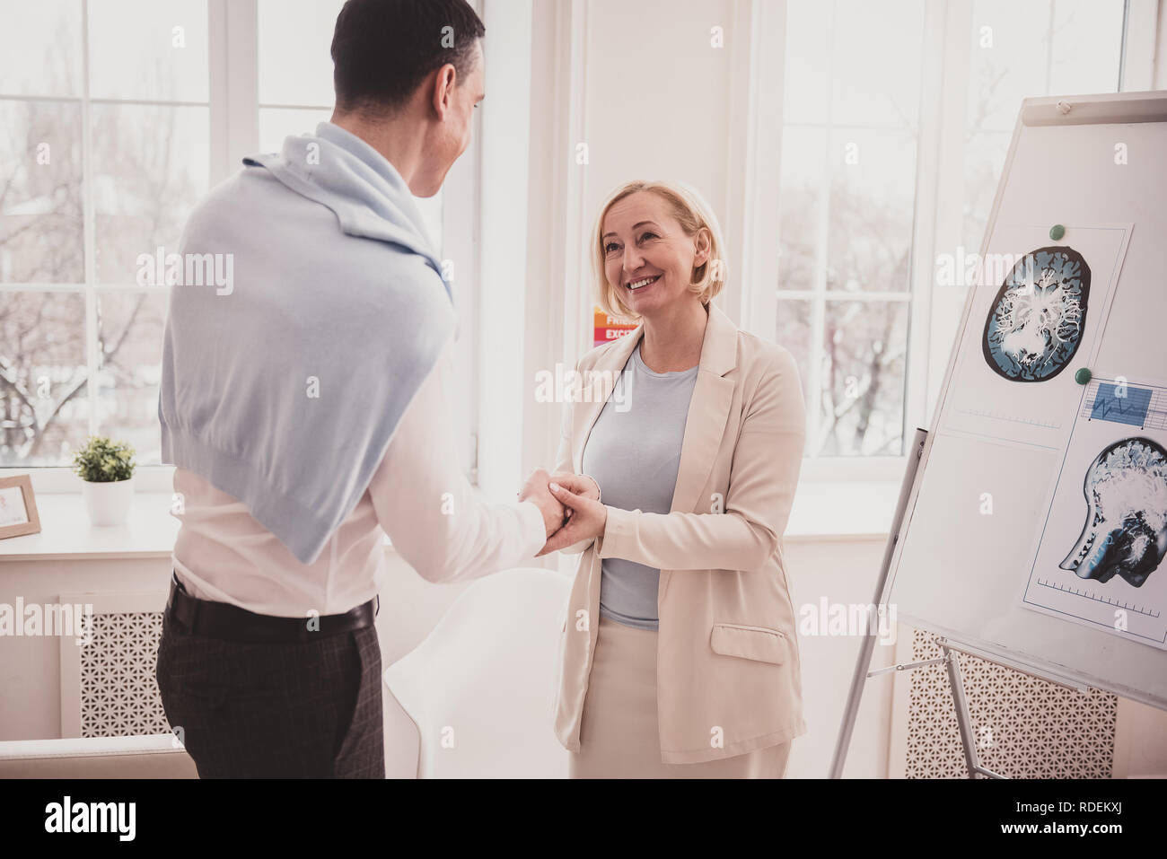 Positive delighted female person shaking hands with visitor Stock Photo ...
