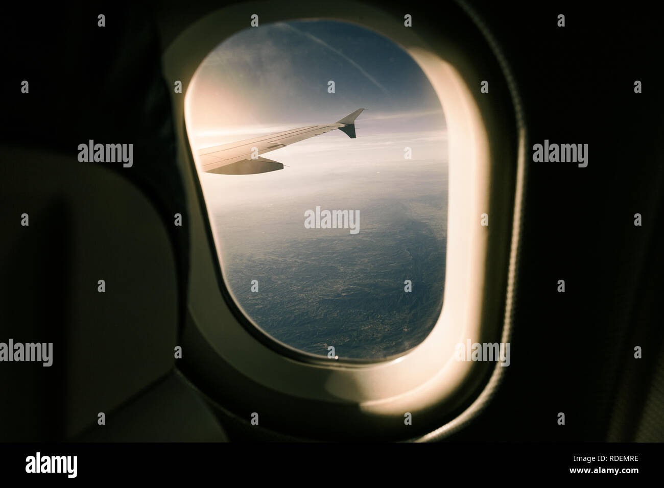 View of sunset from inside the airplane through the window of wing over ...