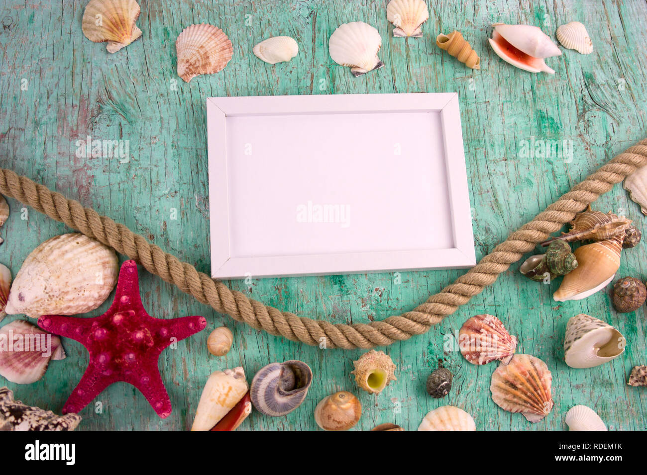 white wooden blank frame,rope and the collection of sea shells on a ...