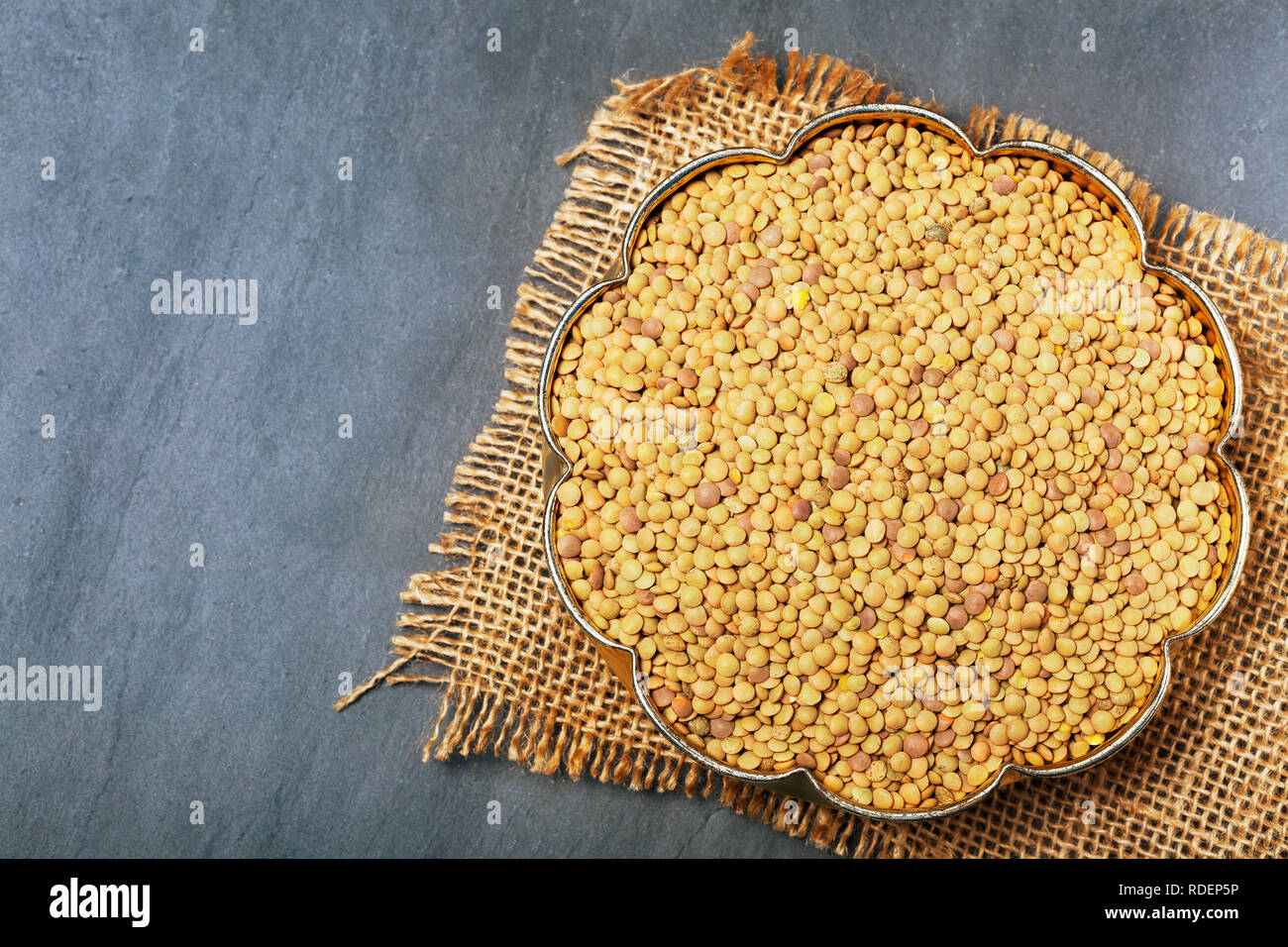 Raw lentils in a golden copper bowl on balck stone background. Healthy ...