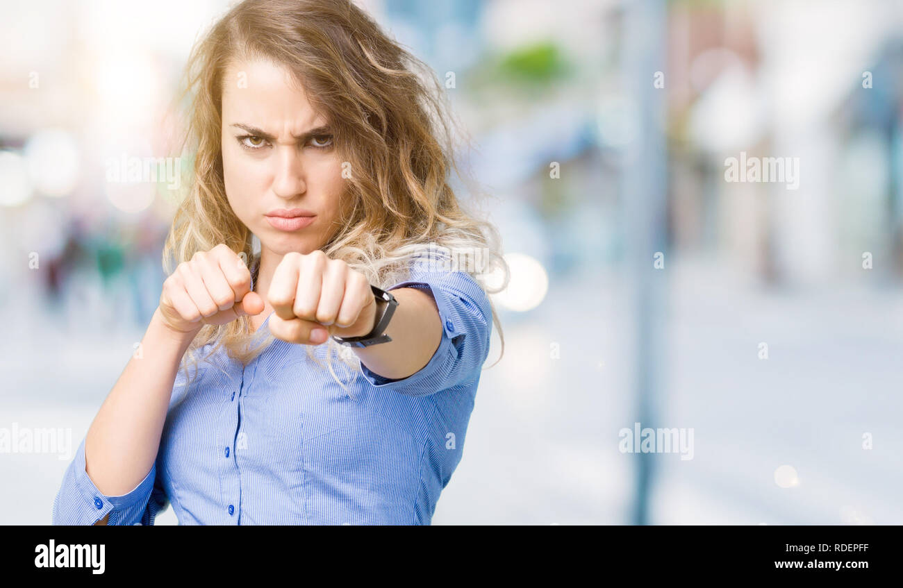 Beautiful young blonde business woman over isolated background Punching ...
