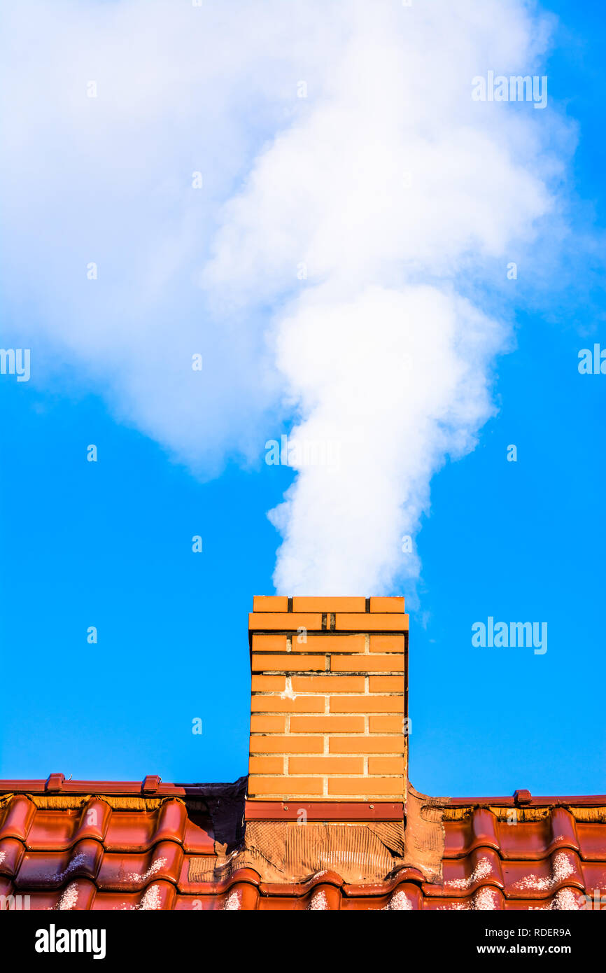 Modern house roof with chimney smoke, air pollution and smog in winter ...