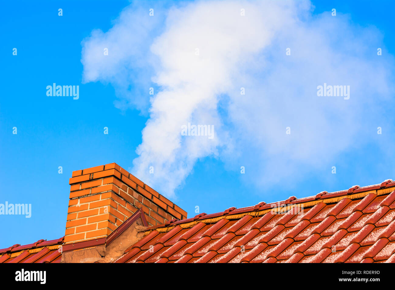 Modern house roof with chimney smoke, air pollution and smog in winter ...