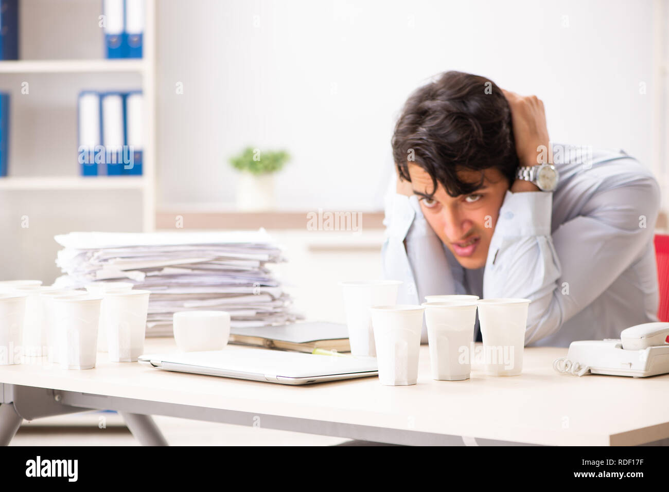 Young employee addicted to coffee Stock Photo - Alamy