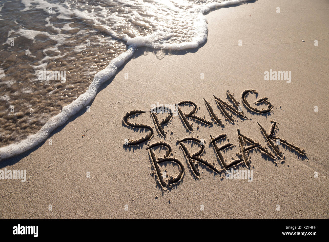 Spring Break message handwritten on the smooth sand of an empty beach ...
