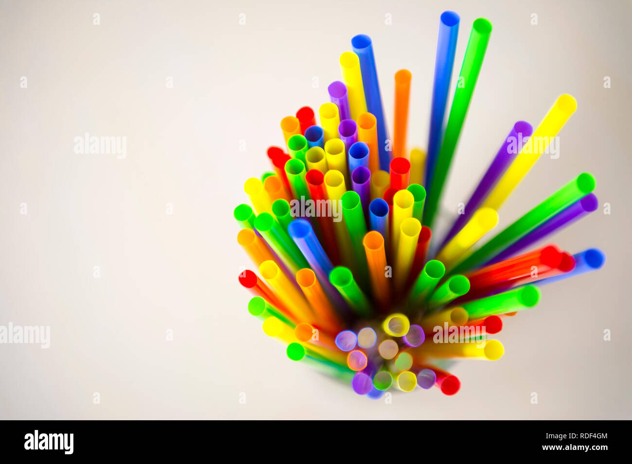 Glass full of brightly colored plastic straws sticking up next to ...