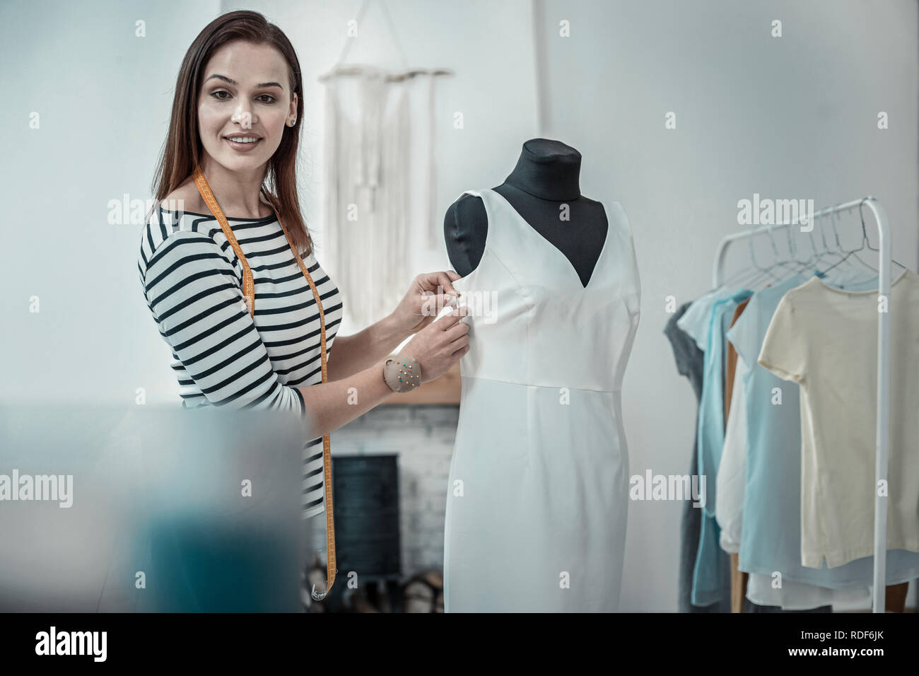 Dark Haired Designer Wearing Striped Shirt Standing Near Dress Form