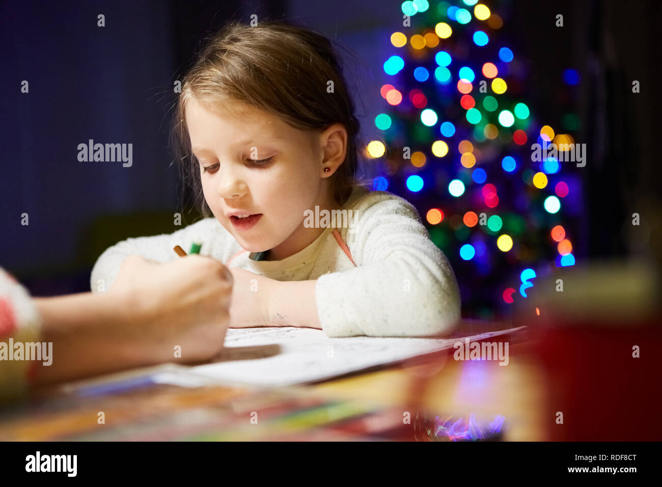 Inspired little girl at the table draw with crayons or do home work ...