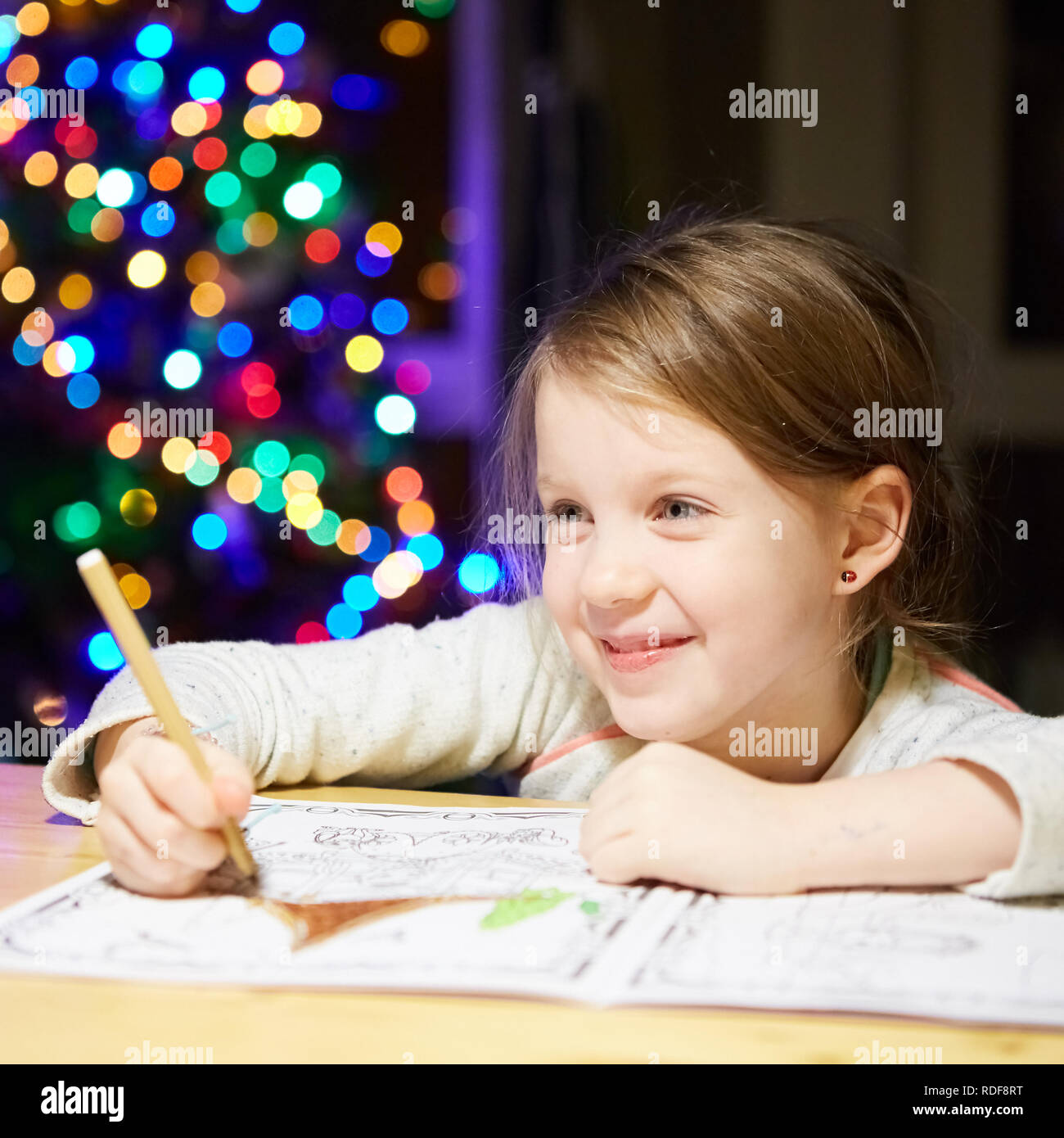 Inspired little girl at the table draw with crayons or do home work ...