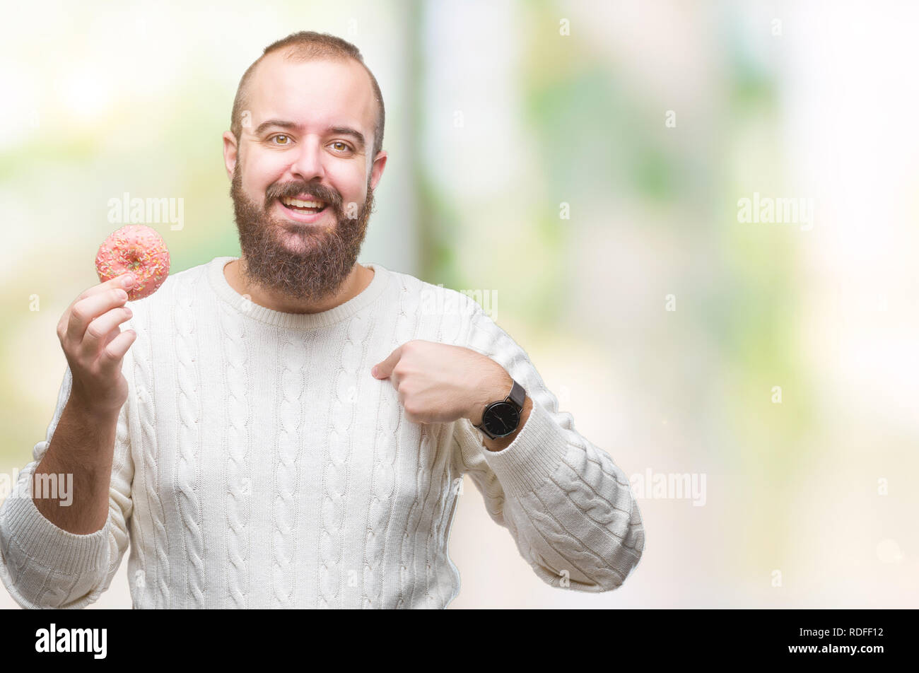 Young caucasian hipster man eating sweet donut over isolated background ...