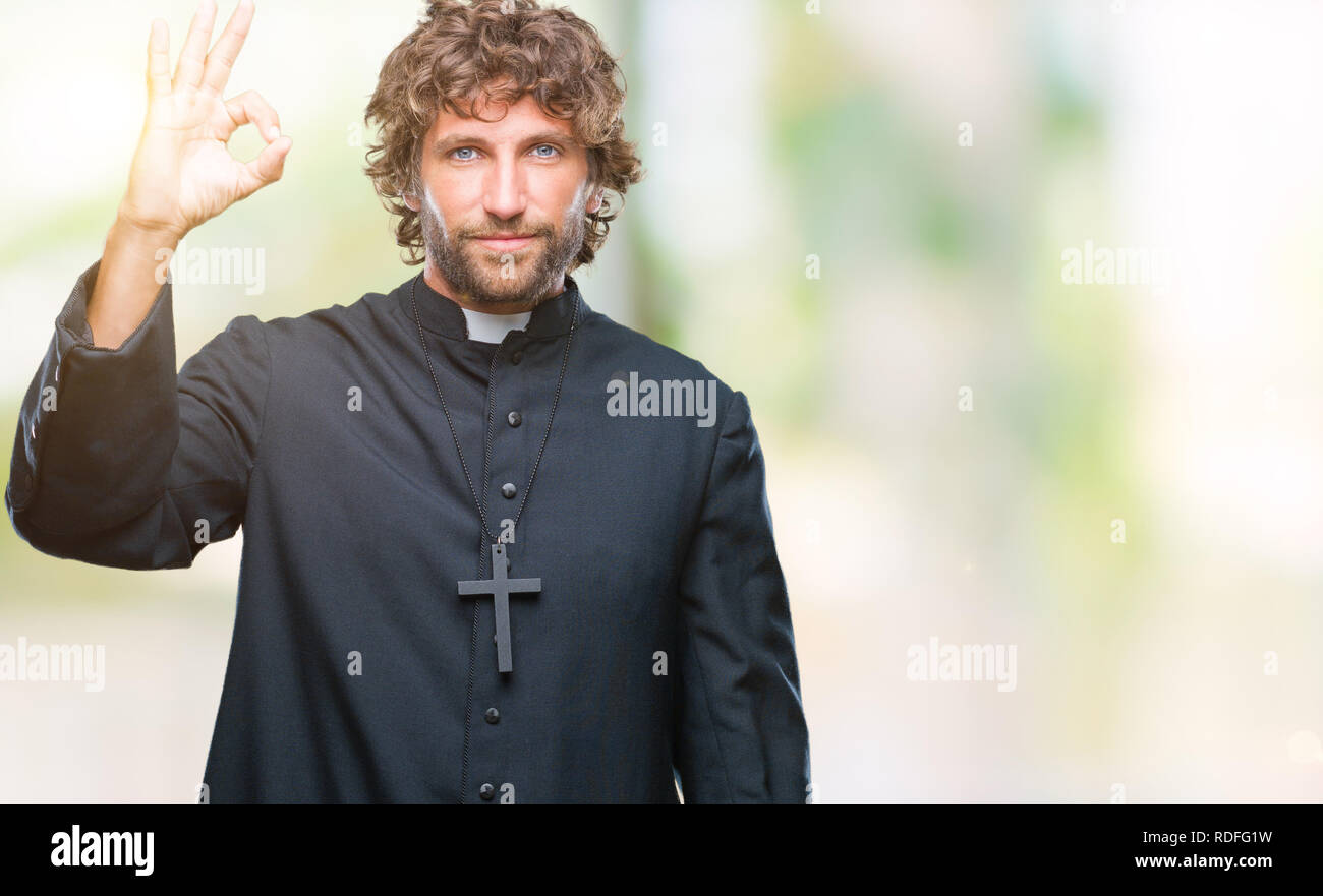 Handsome hispanic catholic priest man over isolated background smiling ...