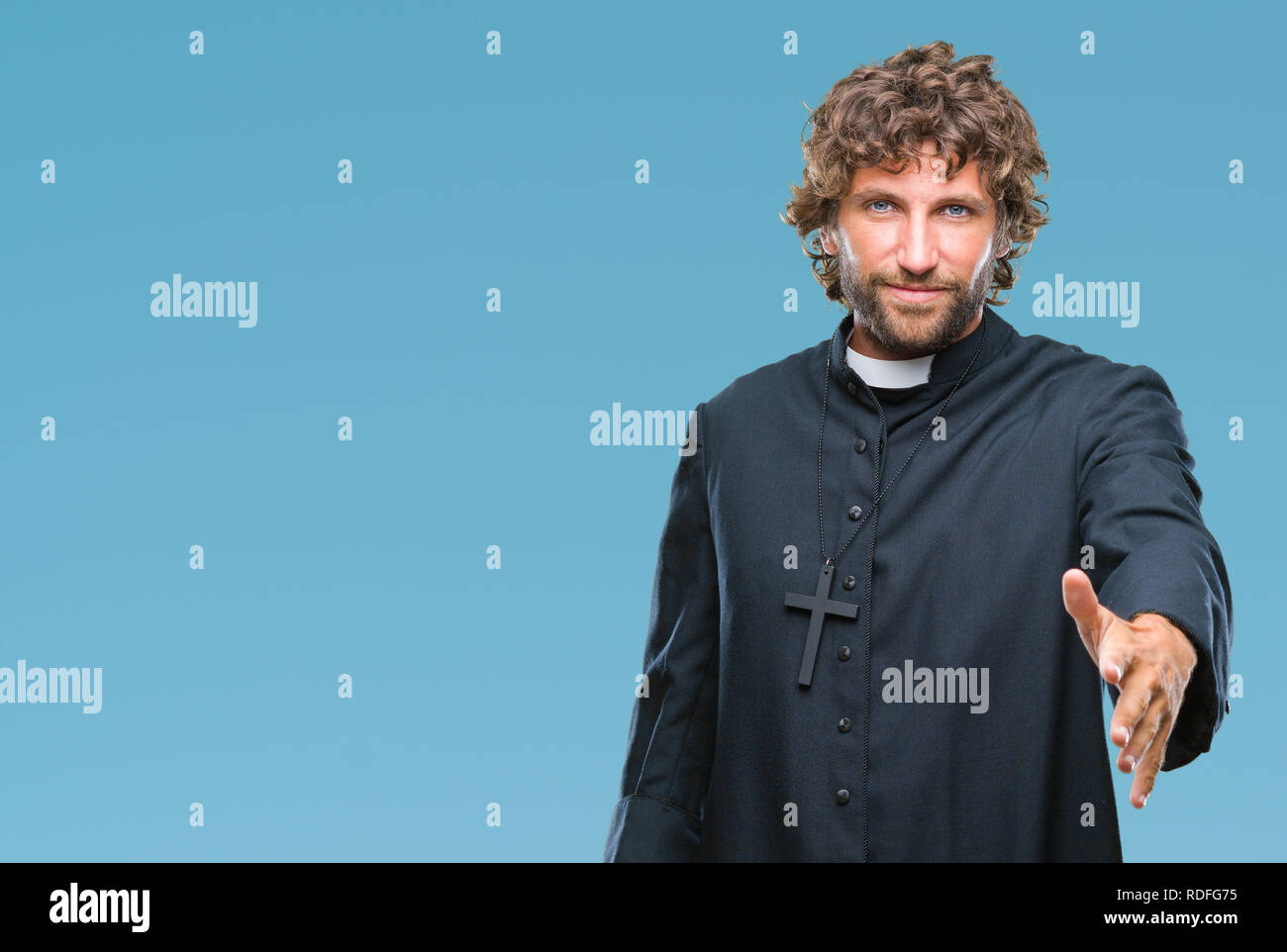 Handsome hispanic catholic priest man over isolated background smiling ...