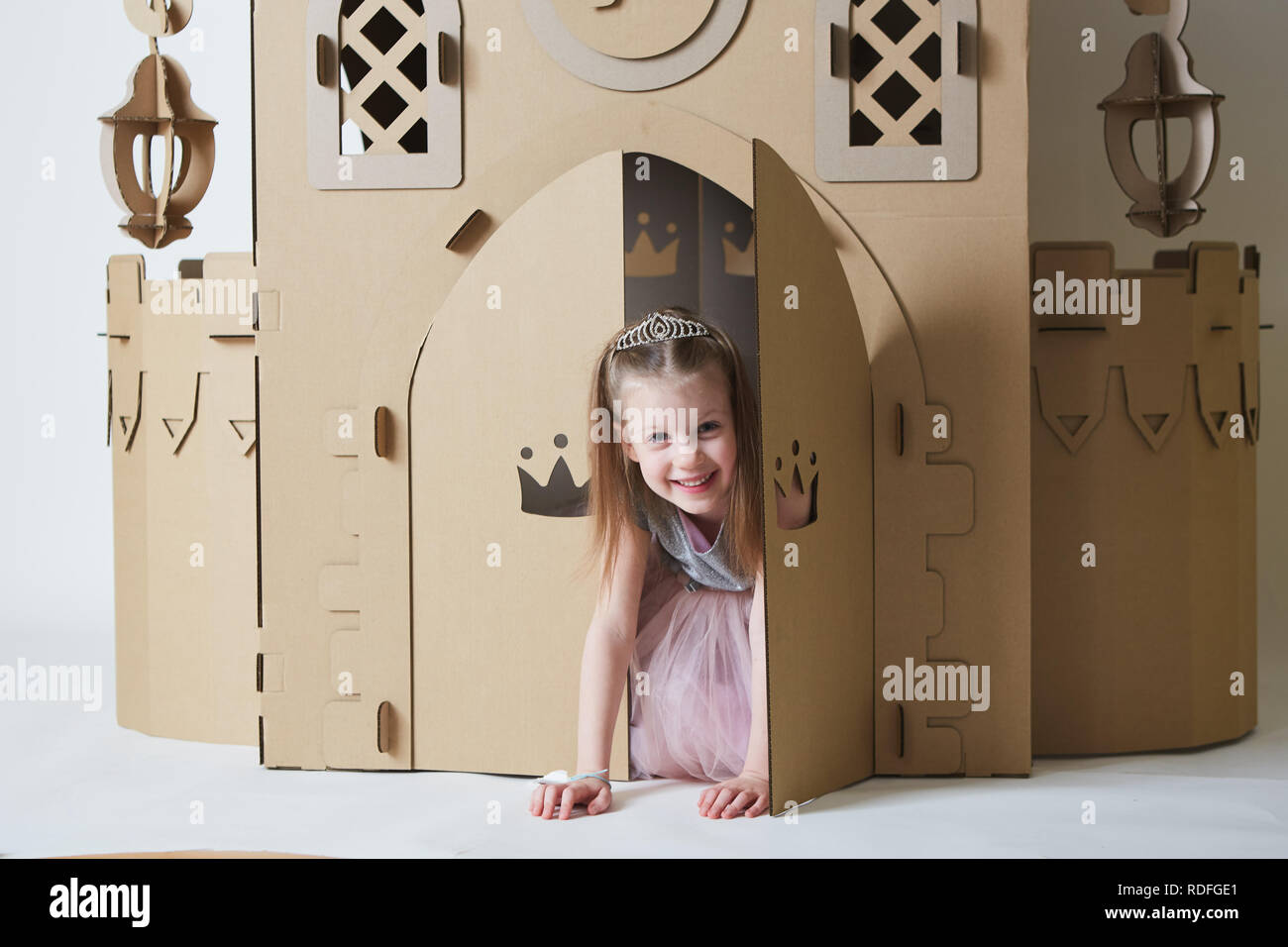 Beautiful little girl in princess dress playing with her toy castle ...