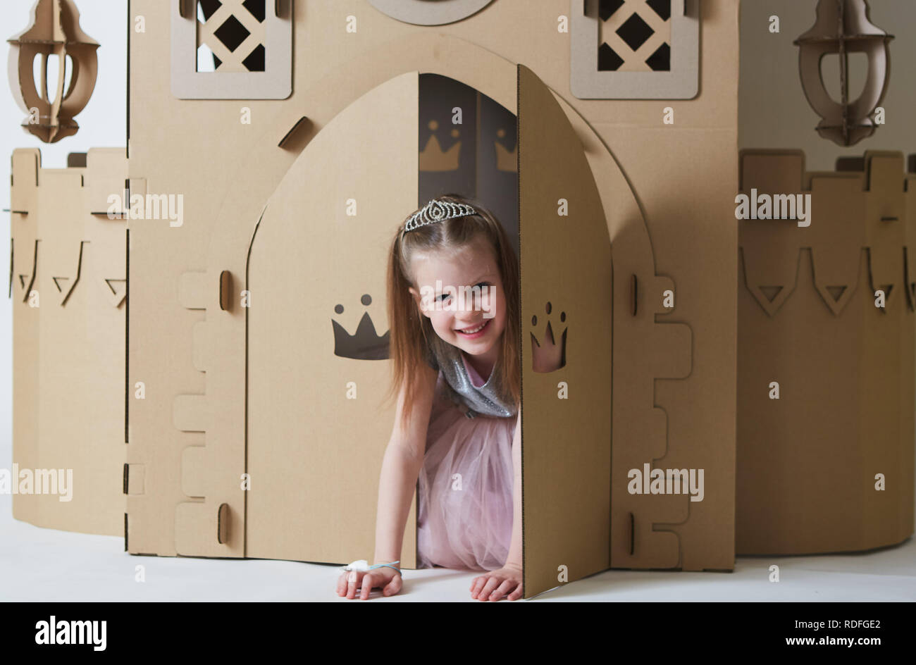 Beautiful little girl in princess dress playing with her toy castle ...
