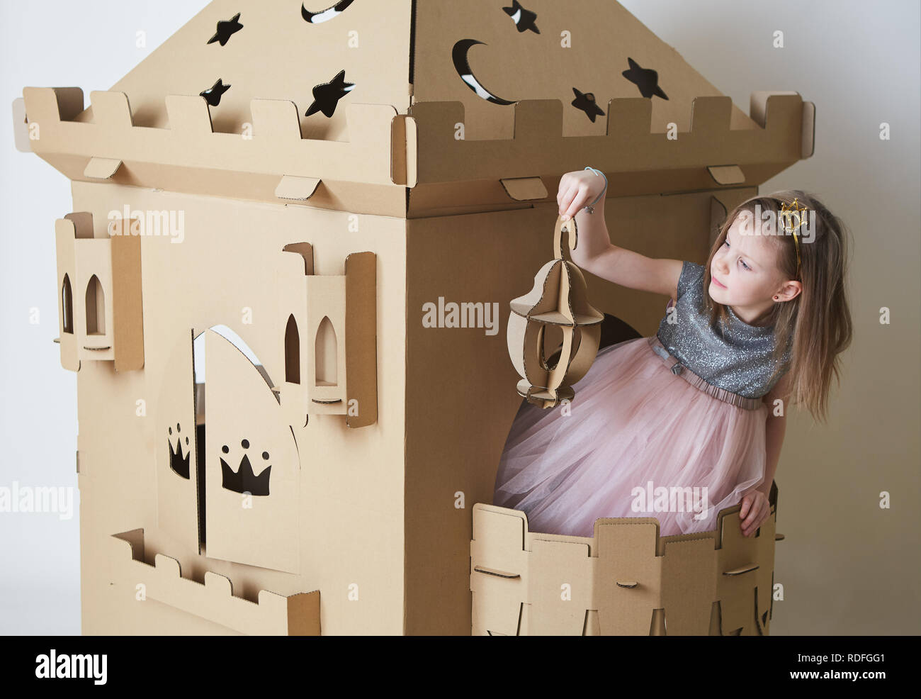 Beautiful little girl in princess dress playing with her toy castle ...