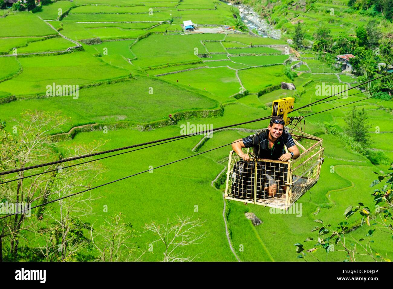 Man in a cargo seat above Hapao rice terraces, part of the world ...