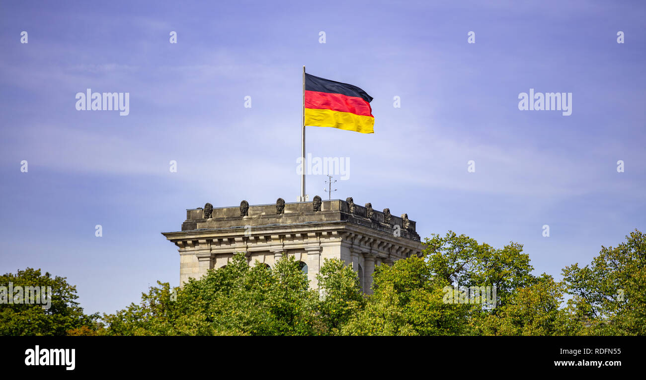 German flag waving on silver flagpole, Reichstag building in Berlin ...