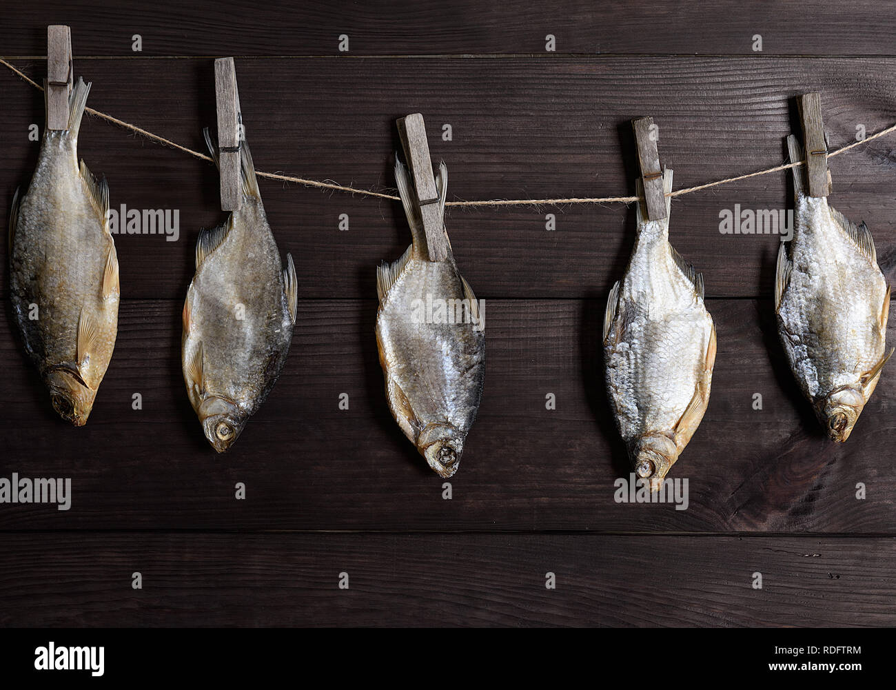 salted fish crucian hanging on a rope hooked on a wooden clothespin ...