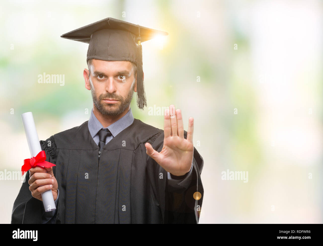 Young handsome graduated man holding degree over isolated background ...